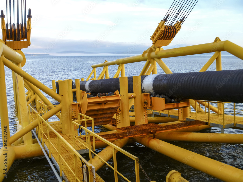 Laying of pipes with pipe-laying barge crane near the shore. Descent of ...