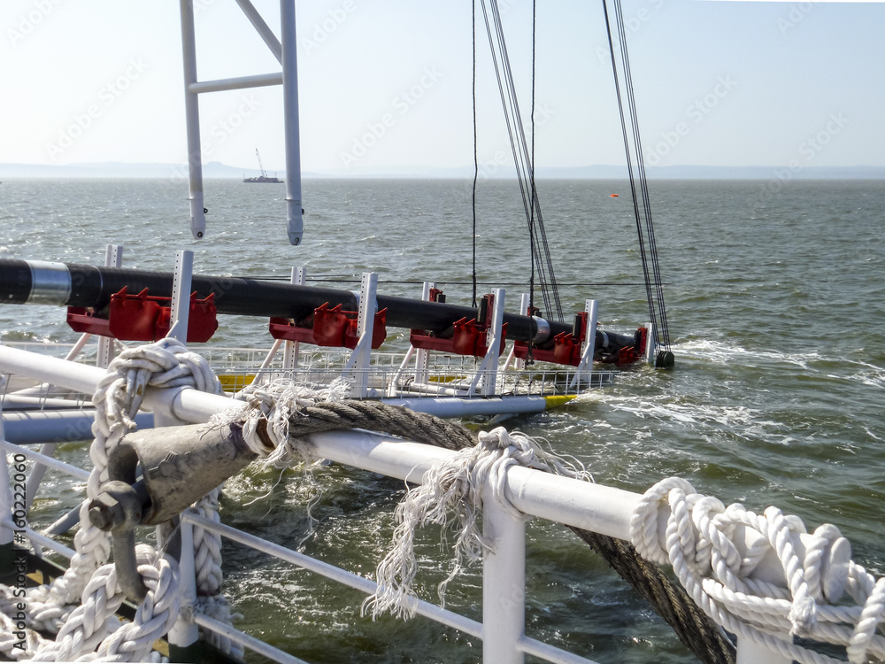 Laying of pipes with pipe-laying barge crane near the shore. Descent of ...