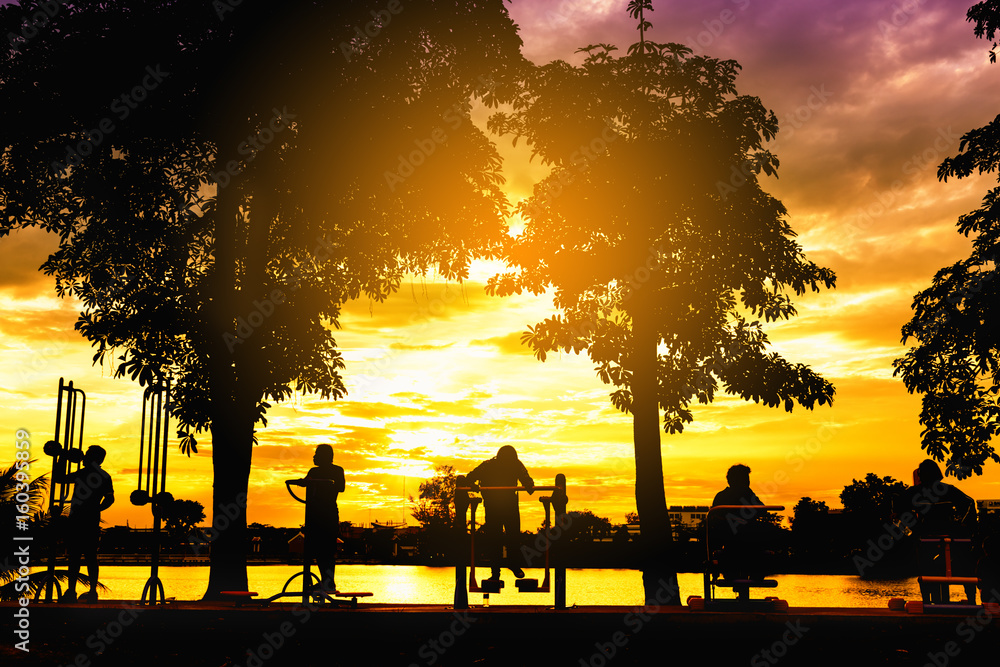 people exercising outdoor with exercise equipment in the park at sunset ...