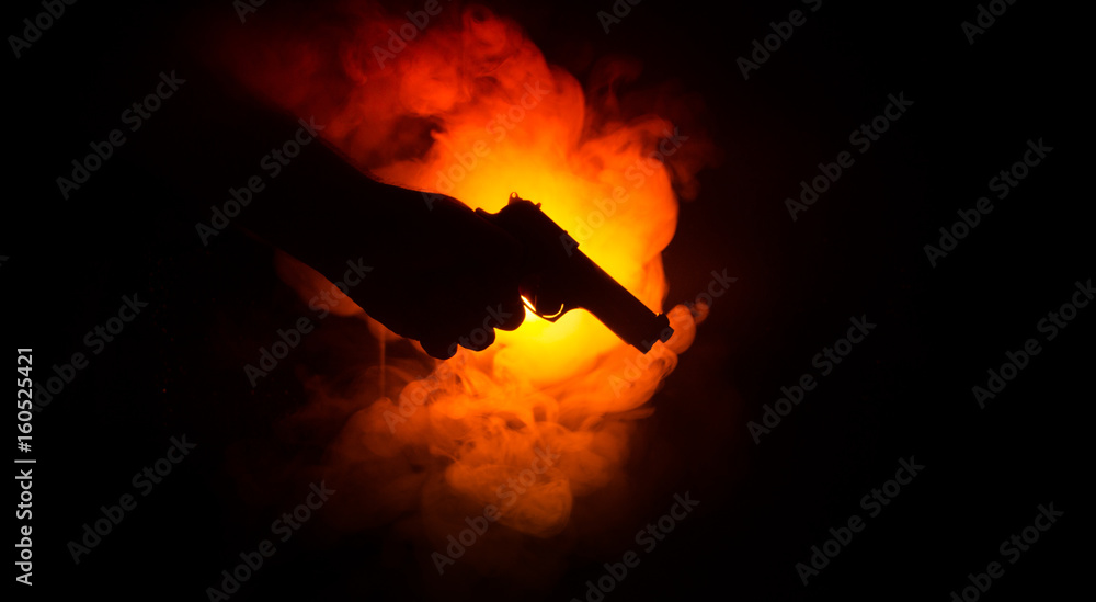 Male hand holding gun on black background with smoke ( yellow orange ...