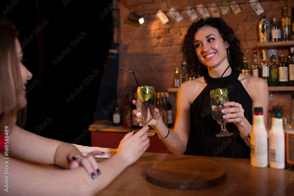 Pretty smiling female bartender offering drinks to guests standing ...