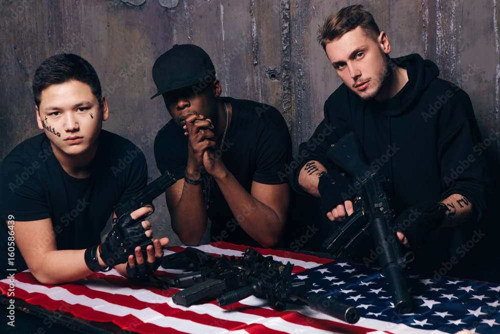 American mercenaries with weapons. Young people with tattoos hold guns ...