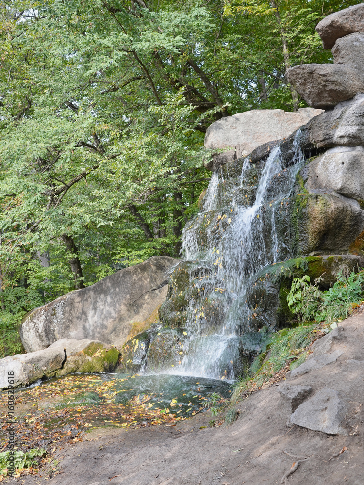 Rushing waterfall flowing over granite boulders in Sofiyivsky Park ...