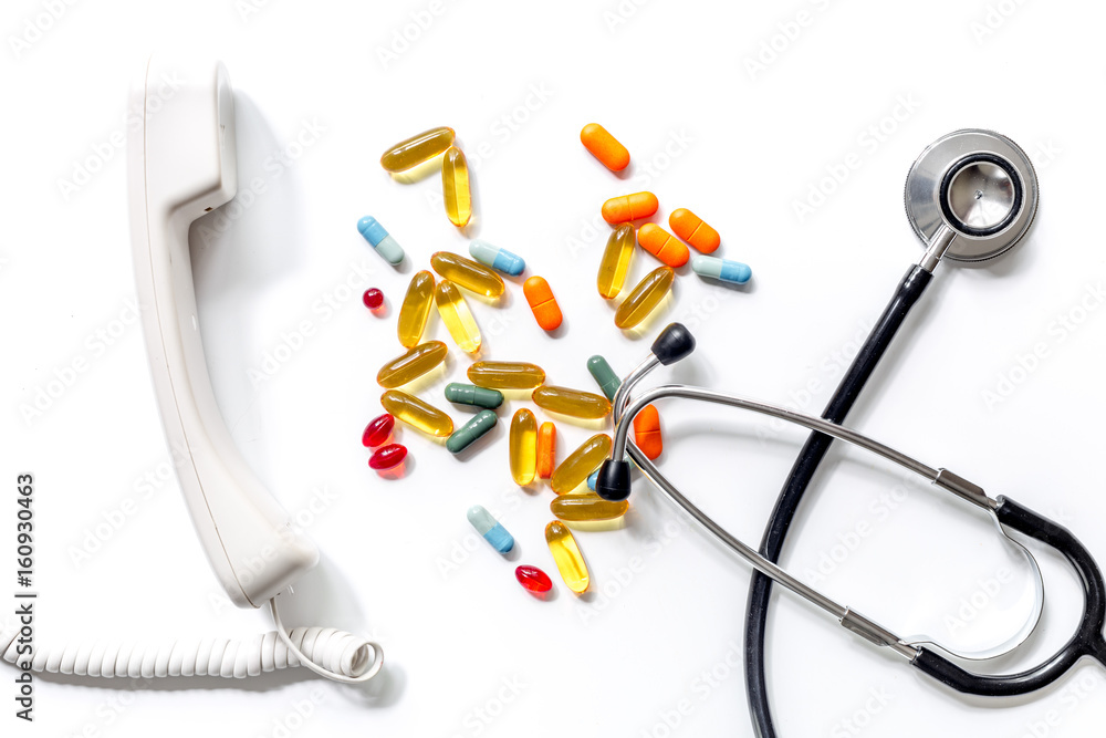 multicoloured pills with phone handset and phonendoscope on white ...