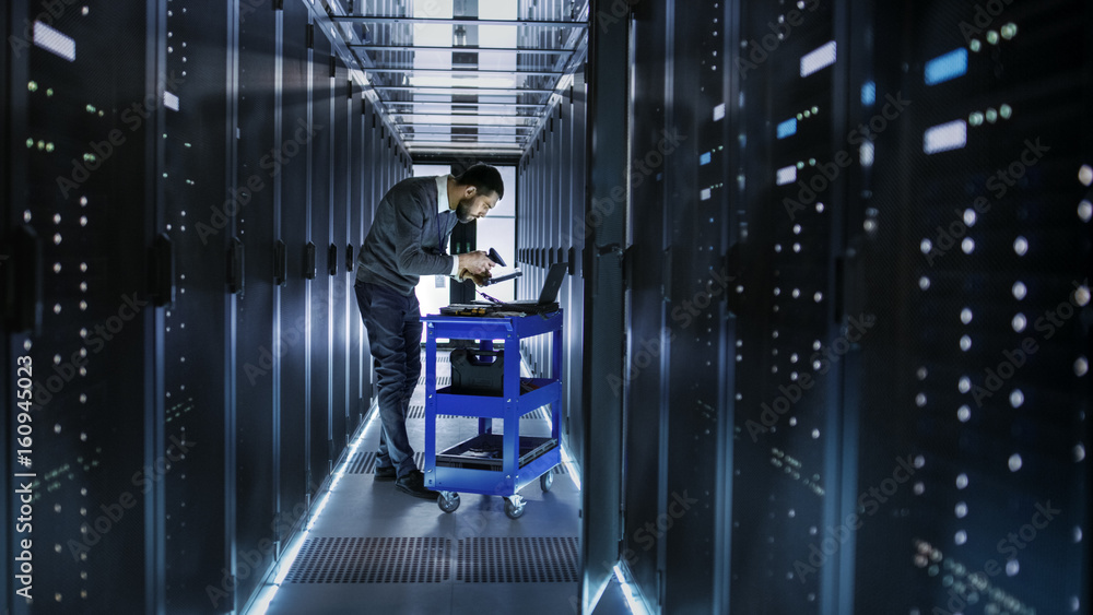 IT Engineer Works on a Laptop and Scans Hard Drives That are Lying on a ...