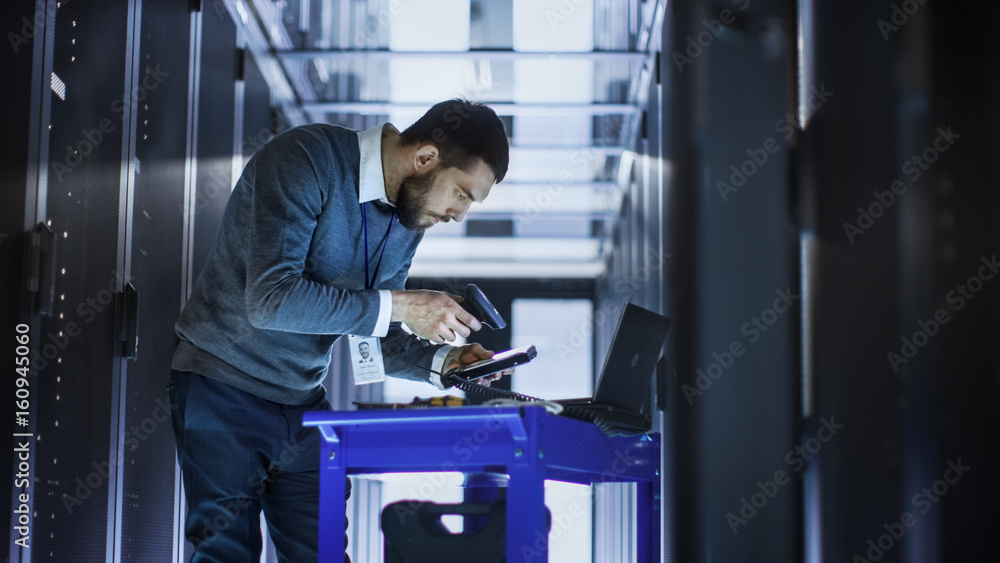 IT Engineer with Tool Cart Working on a Laptop Computer, he Holds a ...