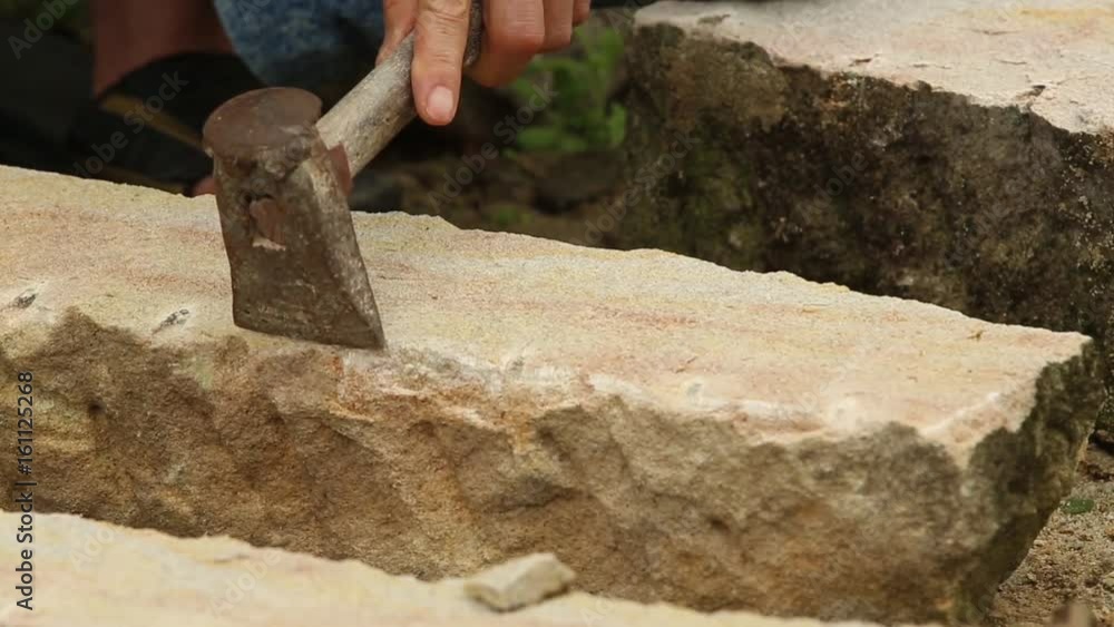 A stonecutter or stonemason is profiling the cut of a stone with a wide ...
