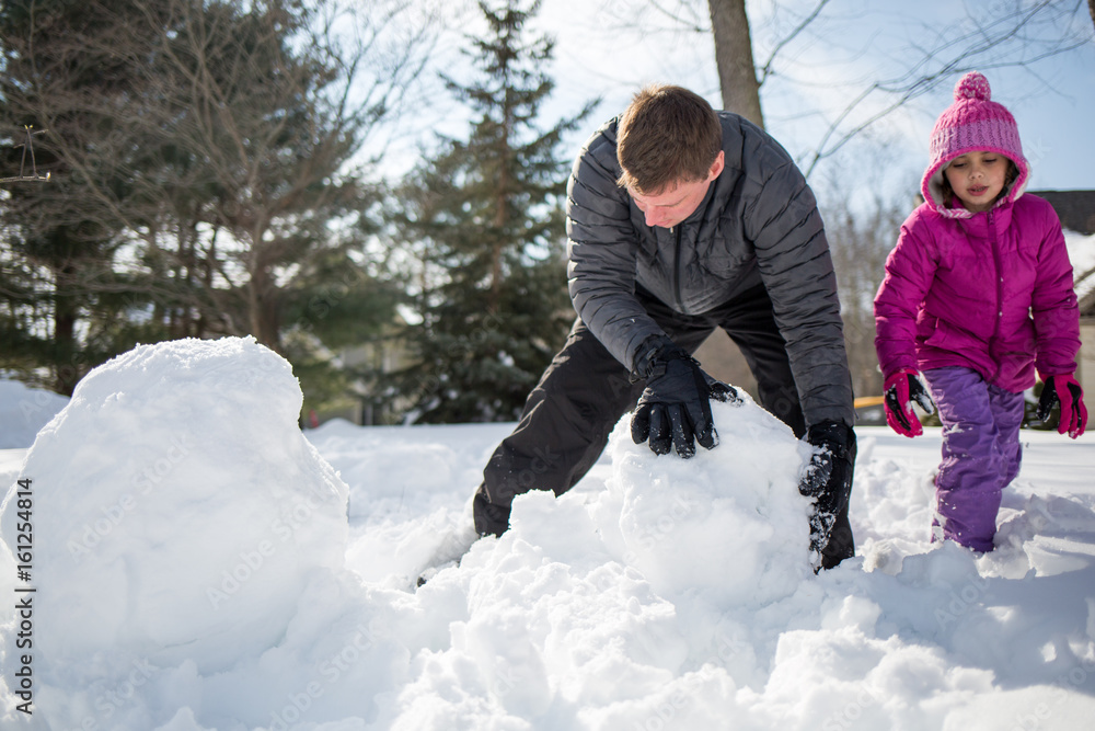 Father and daughter making snowman in snow Stock Photo | Adobe Stock