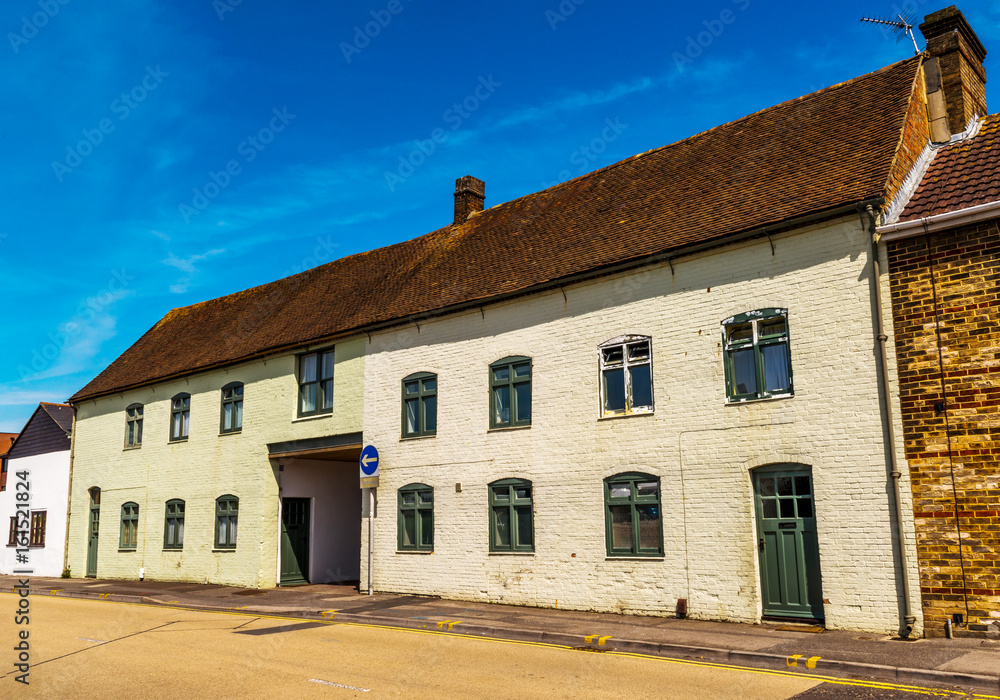 Typical old English buildings, low brick buildings across a narrow ...