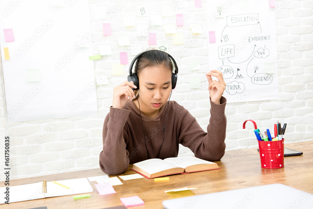 Female student reading book and listening to music Stock Photo | Adobe ...