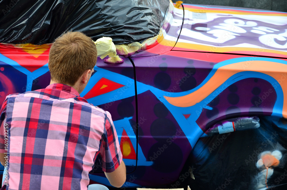 A young red-haired graffiti artist paints a new colorful graffiti on ...