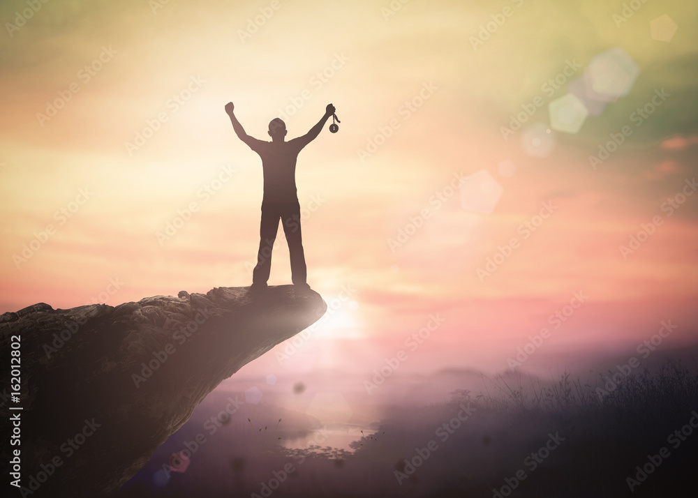 Victory concept: Silhouette champion hand holding gold medal against ...