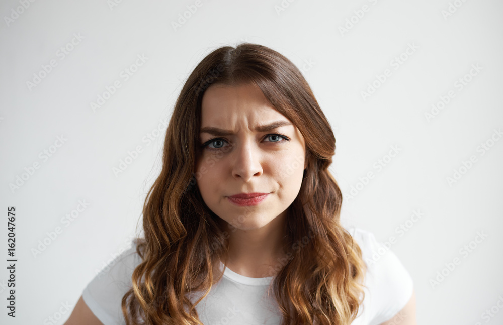 Headshot of outraged young female with blue eyes and long curly hair ...