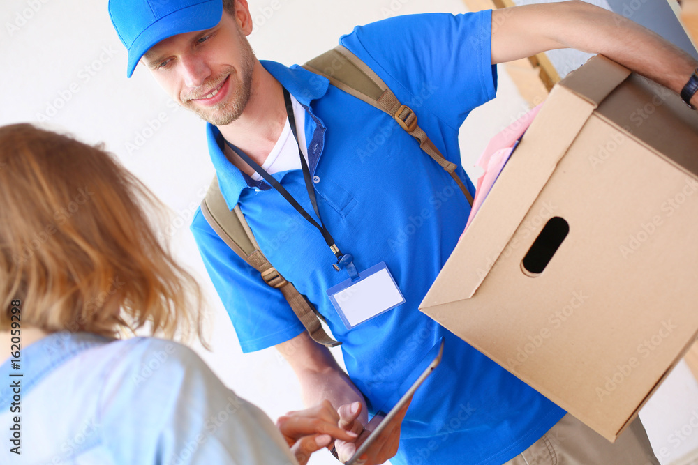 Smiling delivery man in blue uniform delivering parcel box to recipient ...