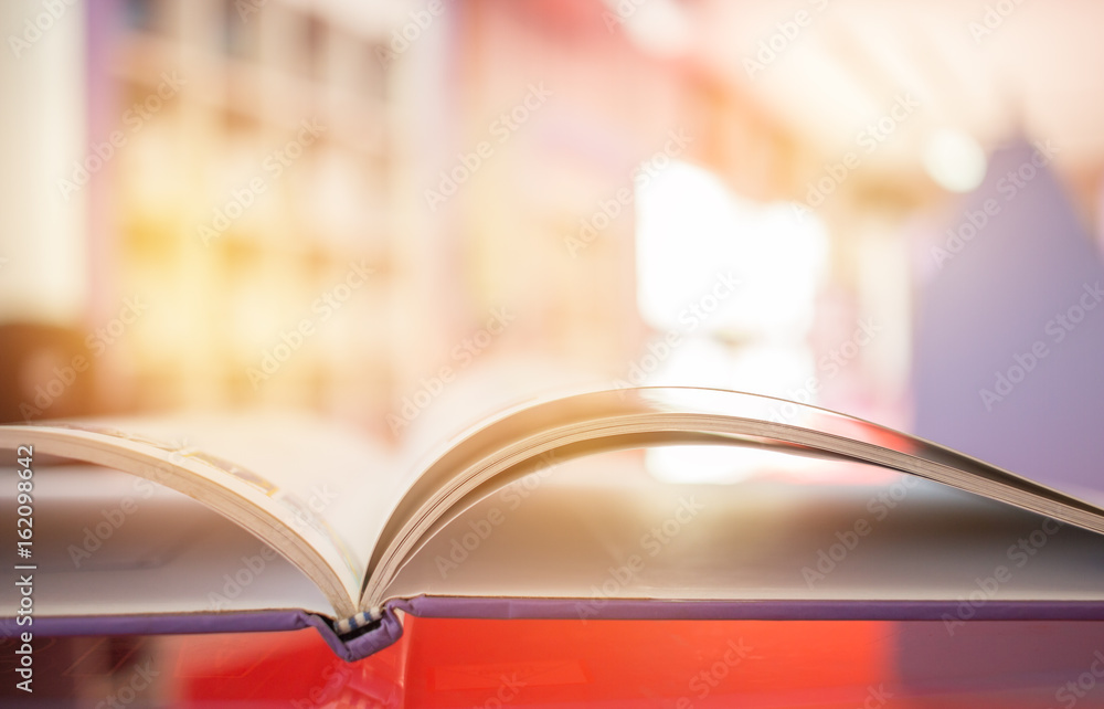 open book light on glass desk in color library room with blurred focus ...