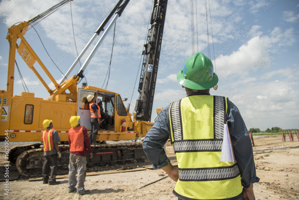 Engineer and foreman looking at heavy machine Assembly concrete pile ...