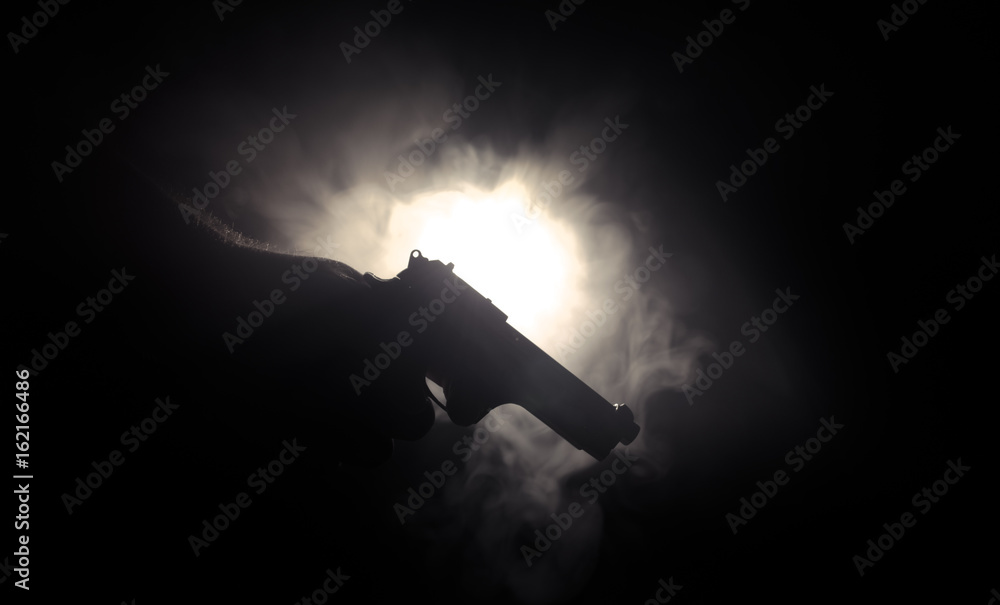 Male hand holding gun on black background with smoke ( yellow orange ...