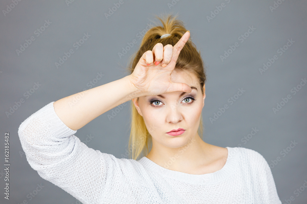 Woman showing loser gesture with L on forehead Stock Photo | Adobe Stock