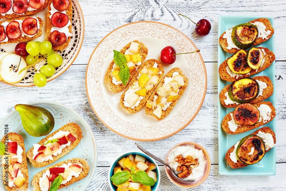 Small toasts with cream cheese and cut pears, peaches, cherry and ...