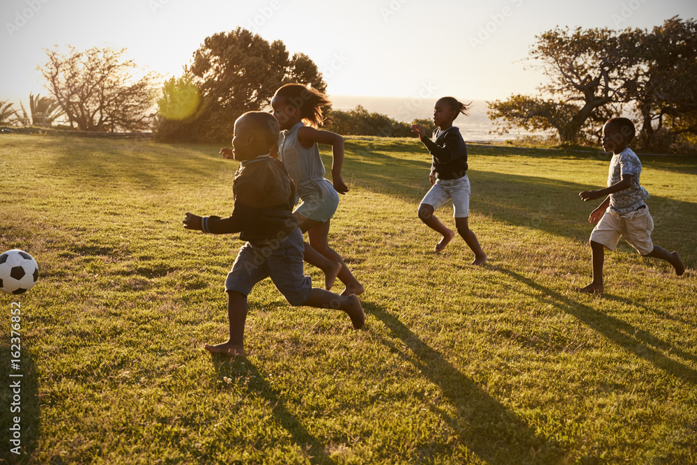 Four elementary school kids playing football in a field Stock Photo ...