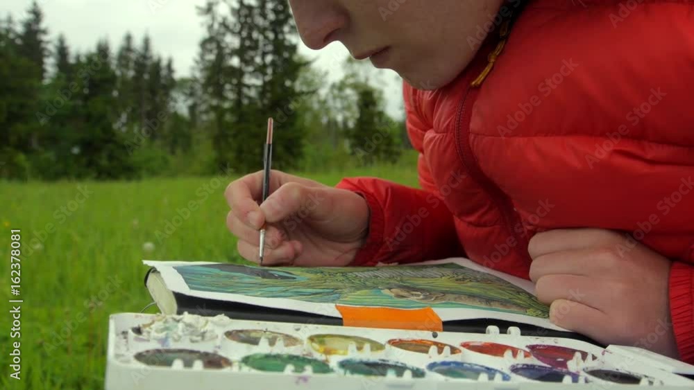 female artist paiting a jungle themed picture with watercolours ...