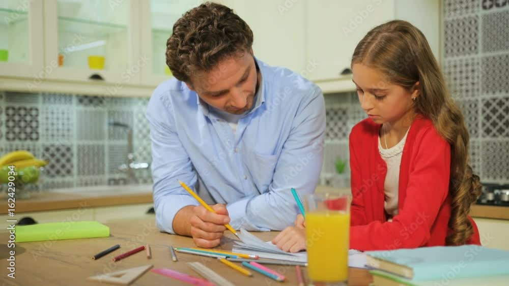 Young father helping his daughter in red sweater doing homework ...
