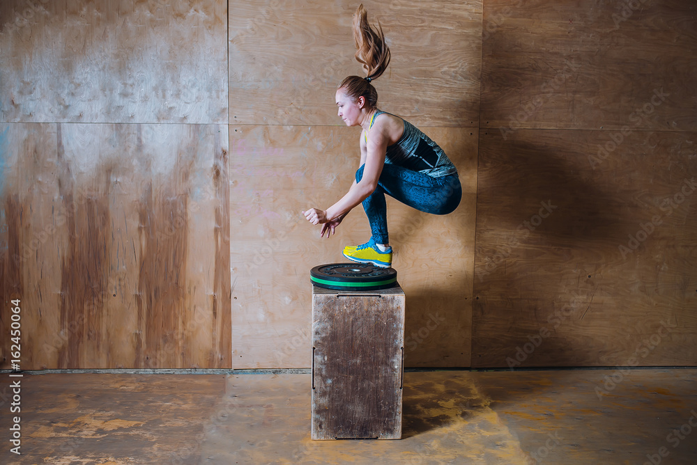 Sporty fit yuong woman jumping over high box during fitness workout ...