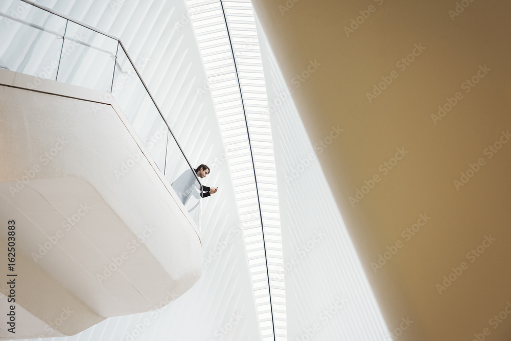 View from below of a man standing on a floating balcony in a large ...
