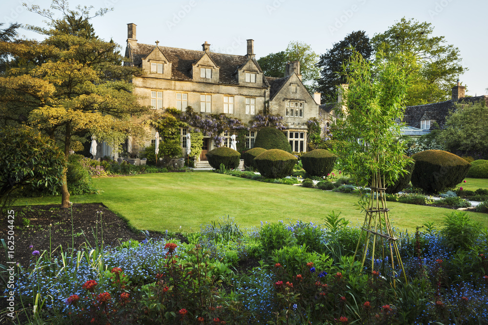 Exterior view of a 17th century country house from a garden with flower ...