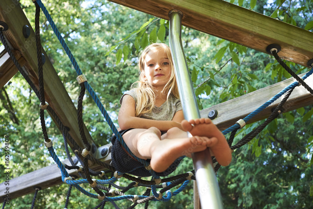 Portrait of a beautiful girl on a rope park among trees. Children ...