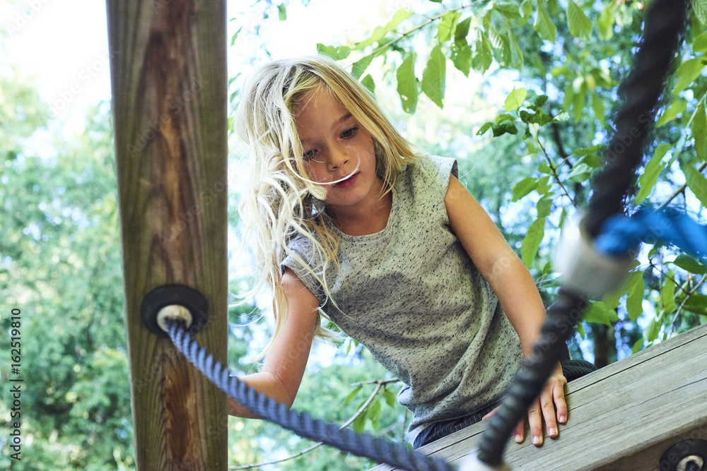 Portrait of a beautiful girl on a rope park among trees. Children ...