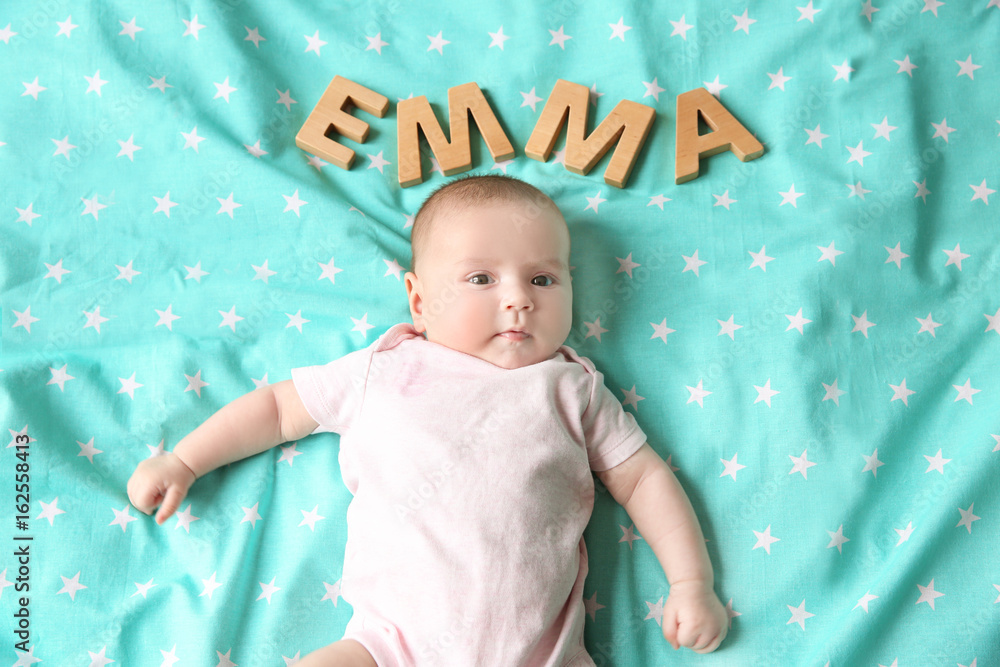 Cute baby with word EMMA lying on bed. Choosing name concept Stock ...