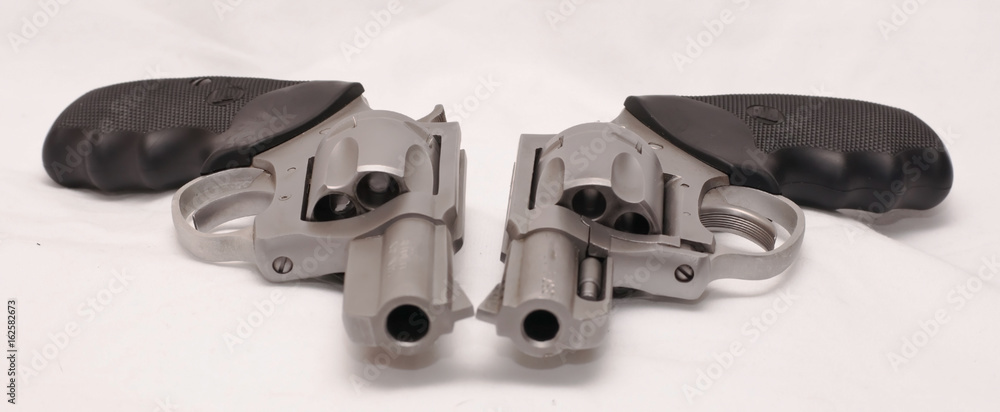 Two stainless revolvers of different calibers with a white background ...