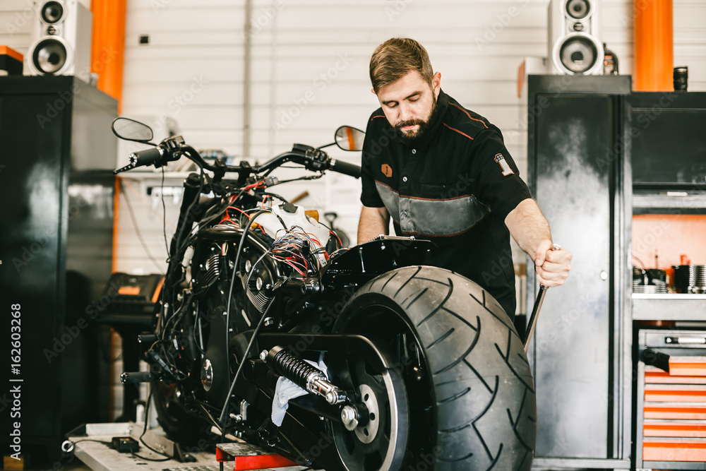 Mechanician changing motorcycle wheel in bike repair shop. Professional ...