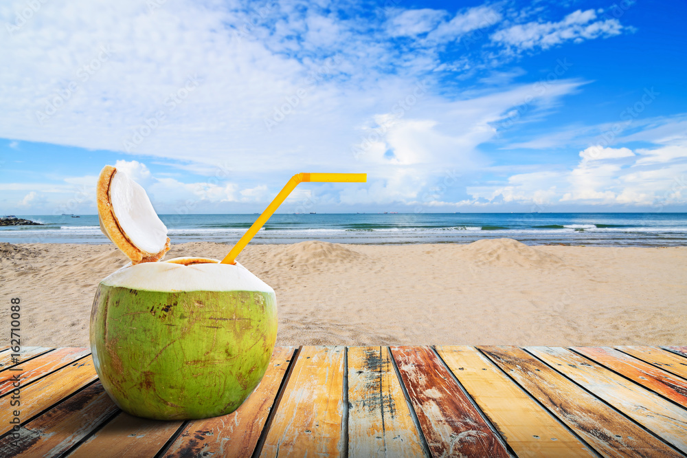 Coconut juice and straw on wood table in summer with blurred beach ...