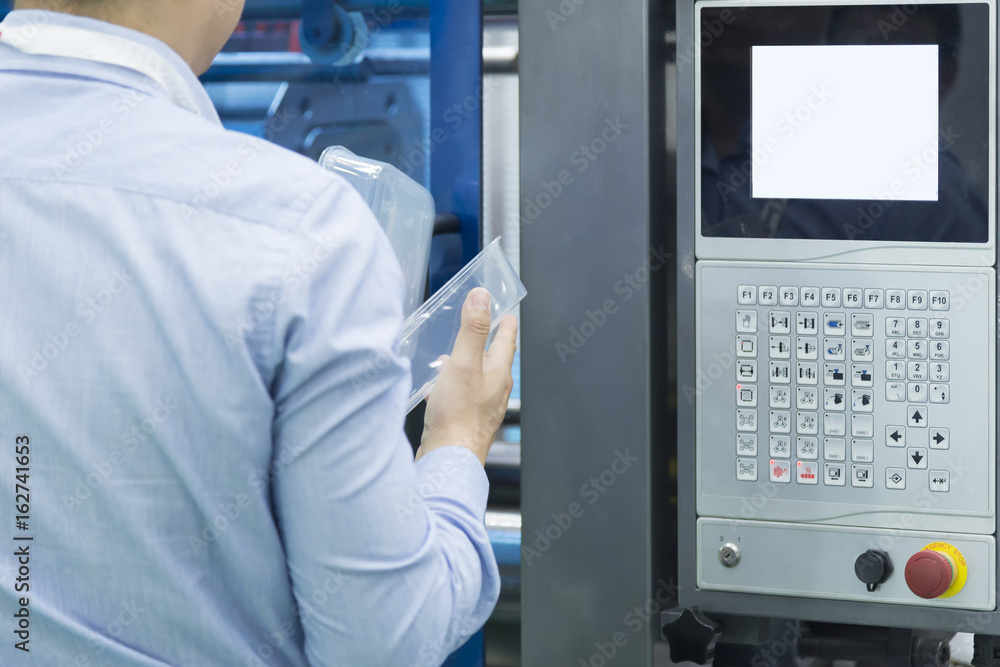 The injection operator put the plastic container from the injection ...