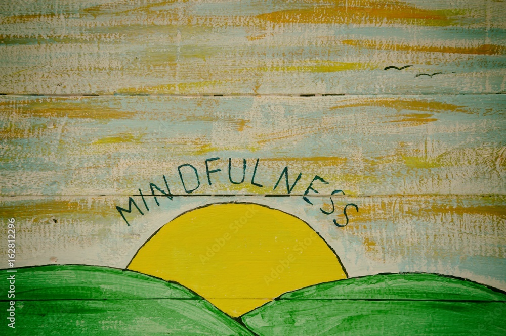 Mindfulness over rising sun and green hills on wood panel background ...