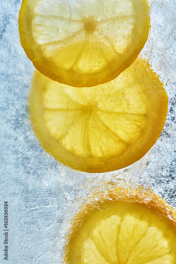 Lemon on the ice. Refreshing summer background of citrus. Yellow lemons ...