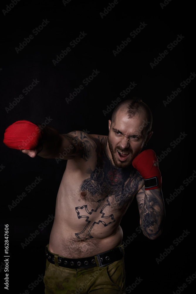 Studio shot of aggressive professional shirtless European boxer boxing ...