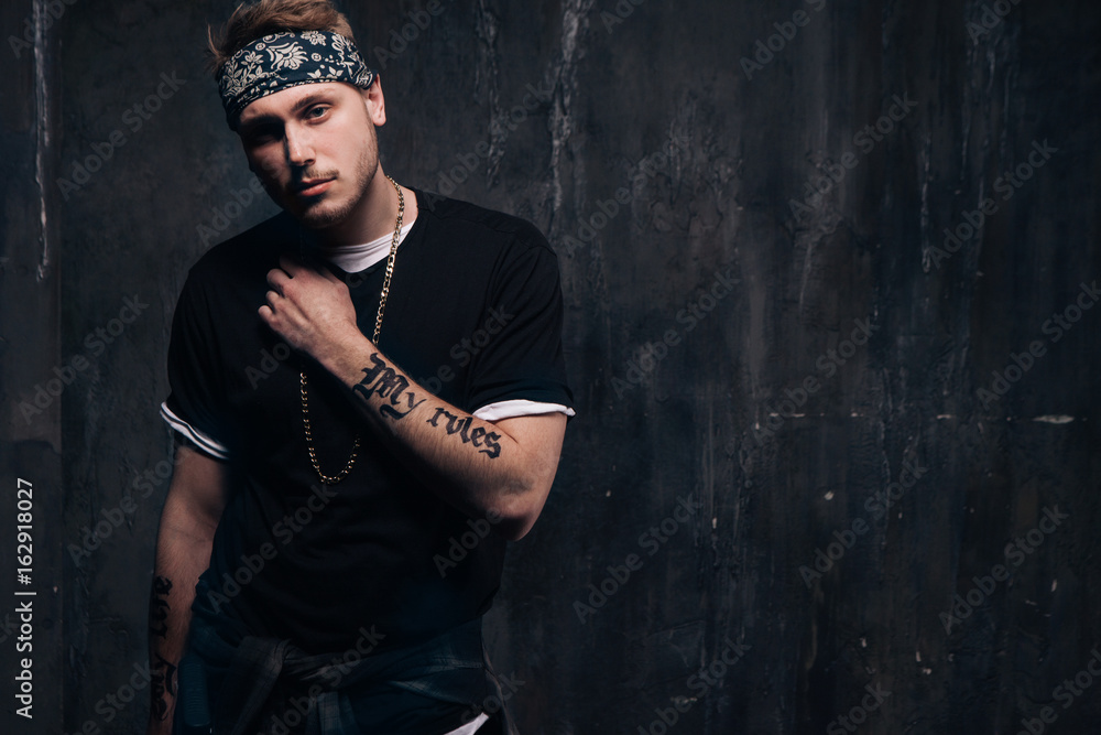 Dangerous tattooed gang member man stay on dark background. American ...