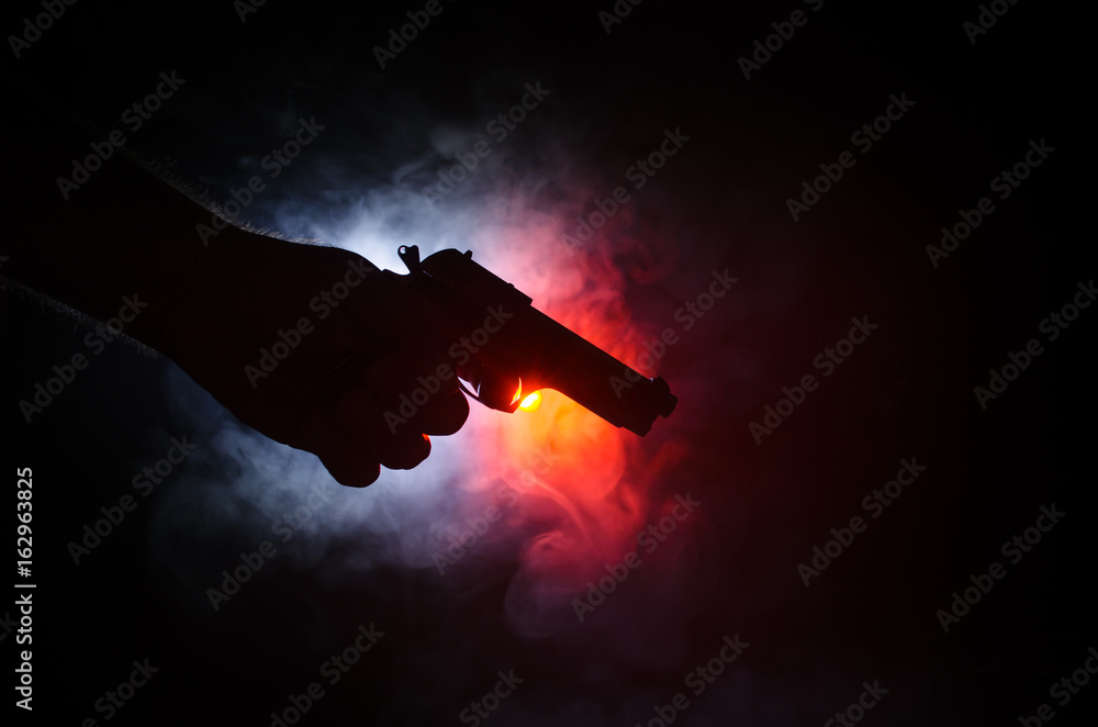 Male hand holding gun on black background with smoke ( yellow orange ...
