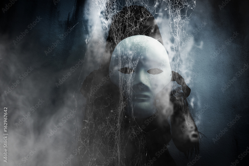 Mysterious woman in black wearing white mask hidden behind spider web ...