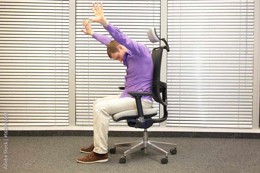 caucasian man stretching arms,exercising on chair in office, healthy ...