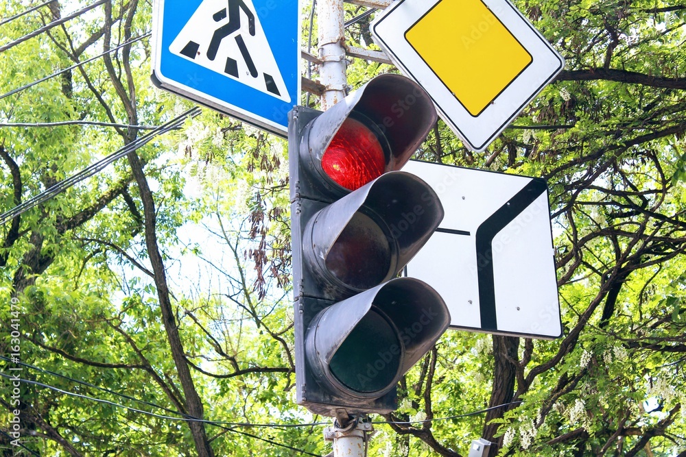 Traffic light and three road signs regulating the traffic in the city ...
