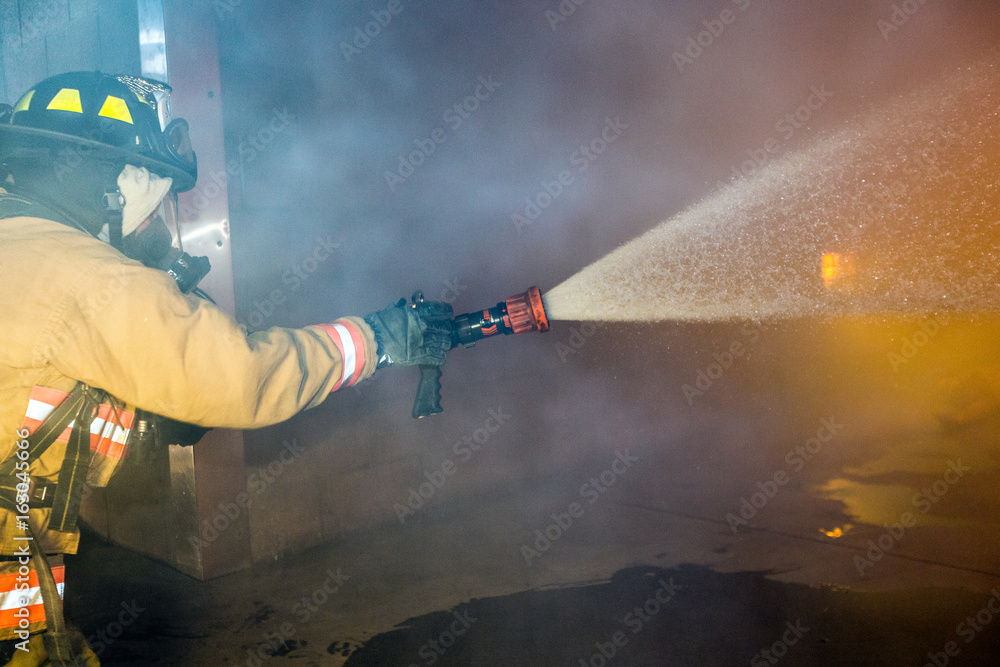Firefighter training using a hose to put out a fire Stock Photo | Adobe ...