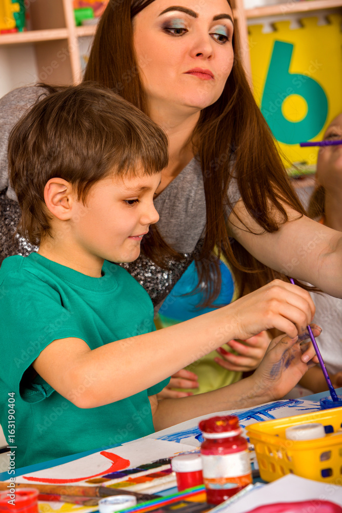 Small students girl and boy with teacher painting in art school class ...
