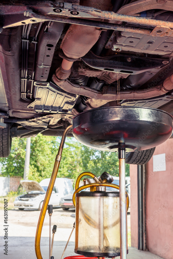 Oil jet flows out into equipment for changing motor oil in a garage ...