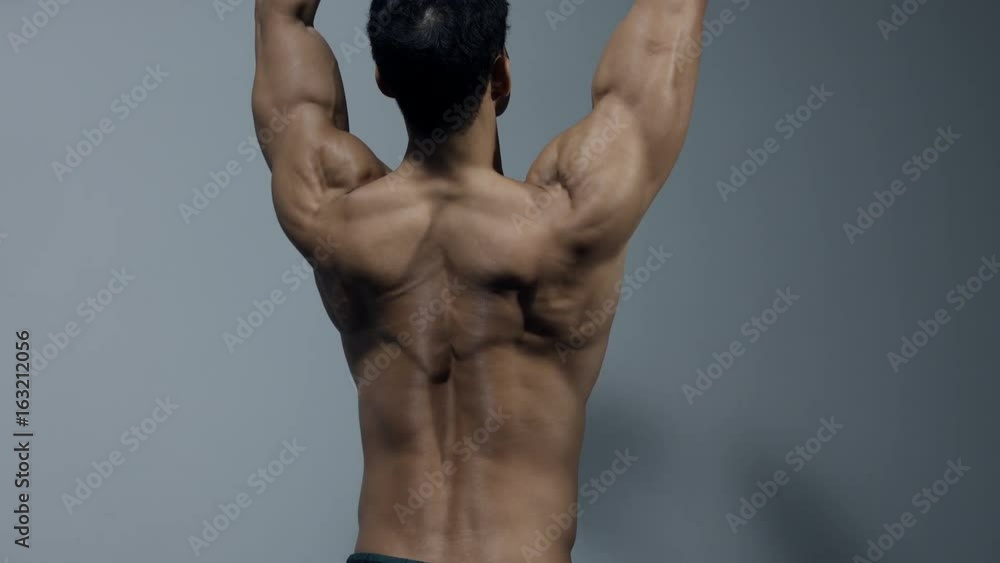 A male fitness model displays his back muscles for the camera. Filmed ...
