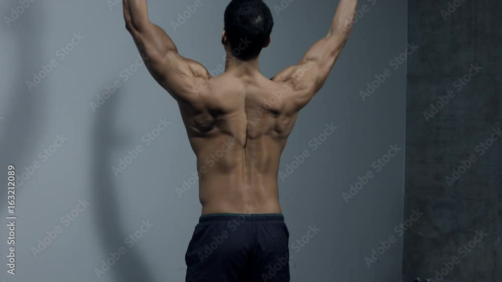 A male fitness model displays his back muscles for the camera. Filmed ...