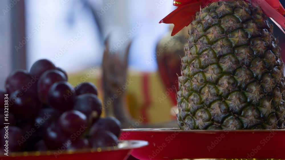 Offering of pineapple, grapes and fruits to the deities in a Chinese ...